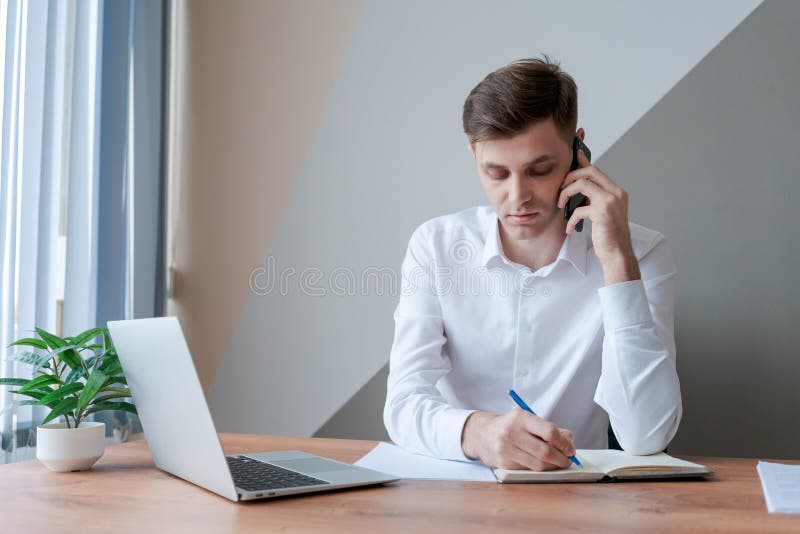 A Man is Sitting at a Desk with a Laptop and a Notebook Stock Image ...