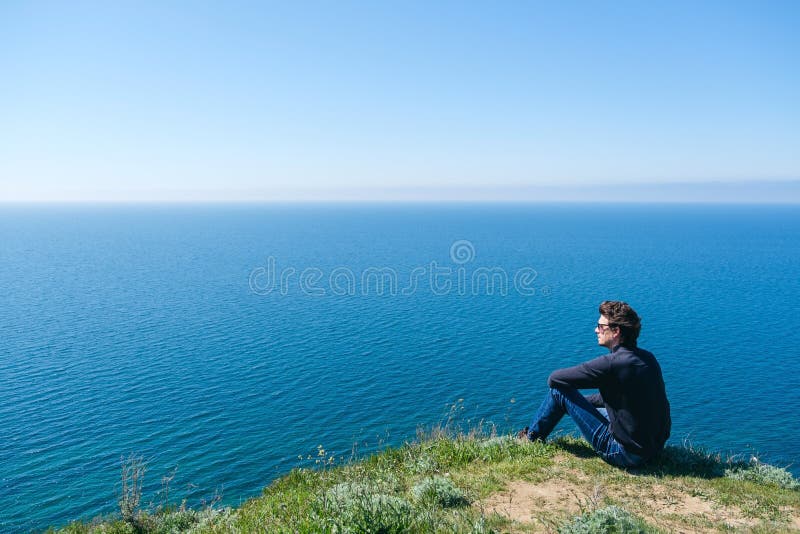 Man Sitting on Edge of Cliff at Edge Stock Image - Image of alone ...