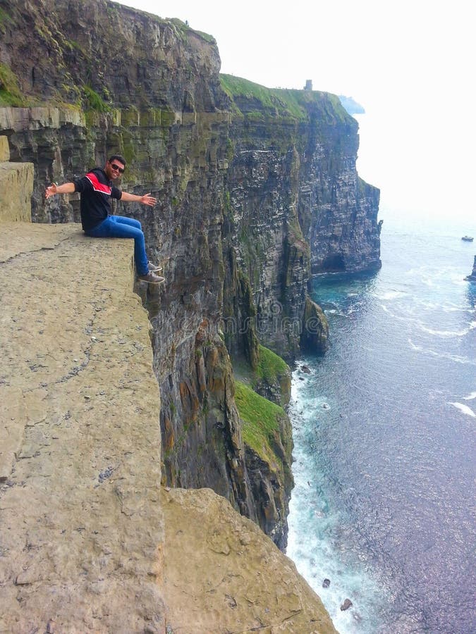 Man Sitting on the Edge of the Cliffs of Moher in Ireland Stock ...