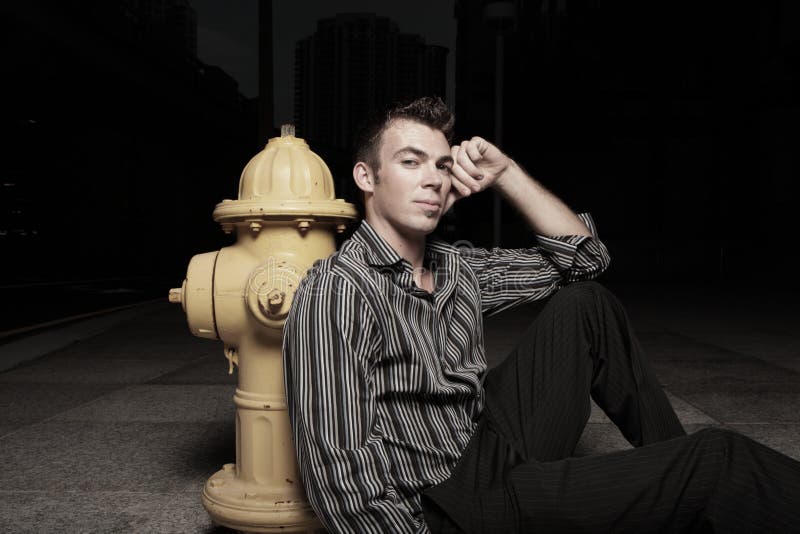 Man Sitting by a Fire Hydrant Stock Photo - Image of yellow, darkness ...