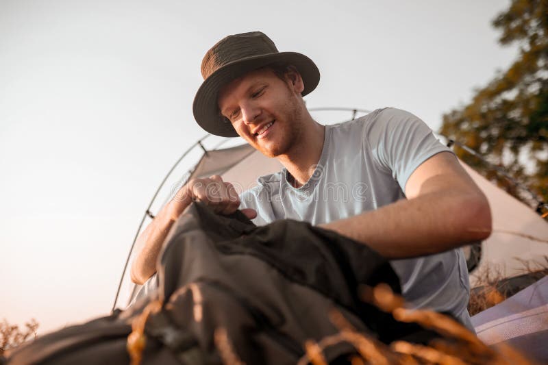 A Man Sitting on the Ground and Packing His Backpack Stock Image ...