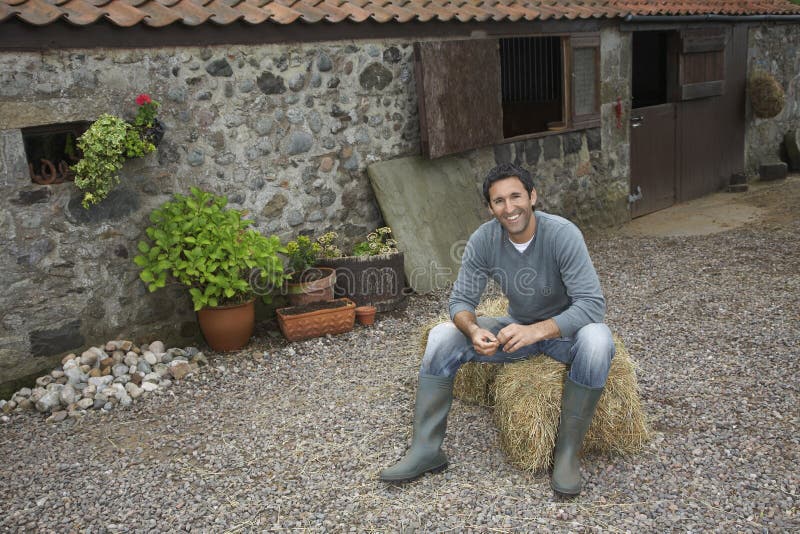Man Sitting on Haybale Outside Stable Stock Image - Image of lifestyle ...