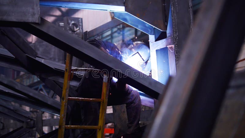 A Man Sitting at His Workplace and Using a Welding Machine. Bright Blue ...