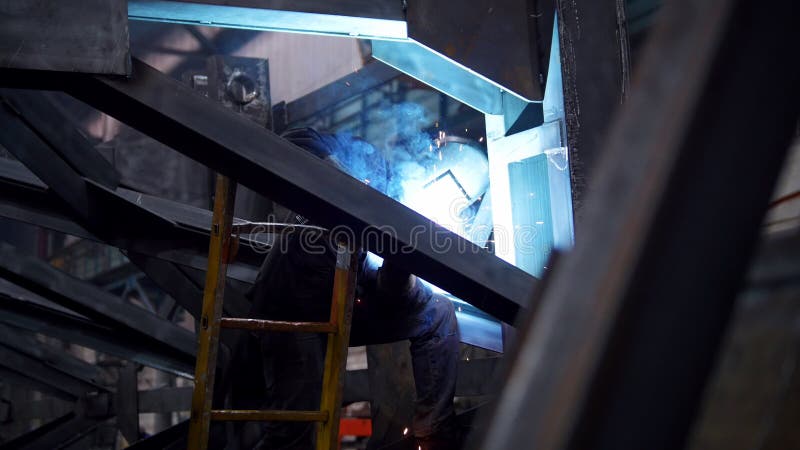 A Man Sitting at His Workplace and Using a Welding Machine. Bright Blue ...