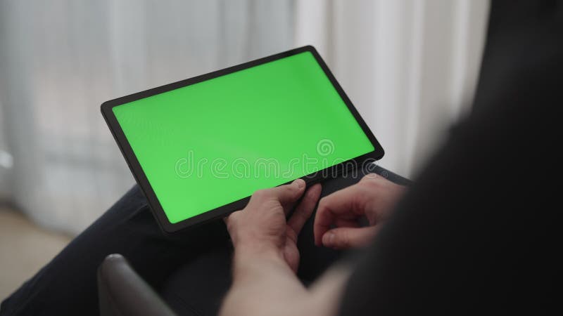 Man Sitting Indoors on a Chair with Tablet Pc with Green Screen Stock ... Man Sitting Indoors on a Chair with Tablet Pc with Green Screen Stock ...
