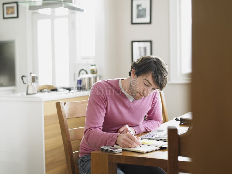 Man Sitting in Kitchen Writing in Notebook Stock Image - Image of ...