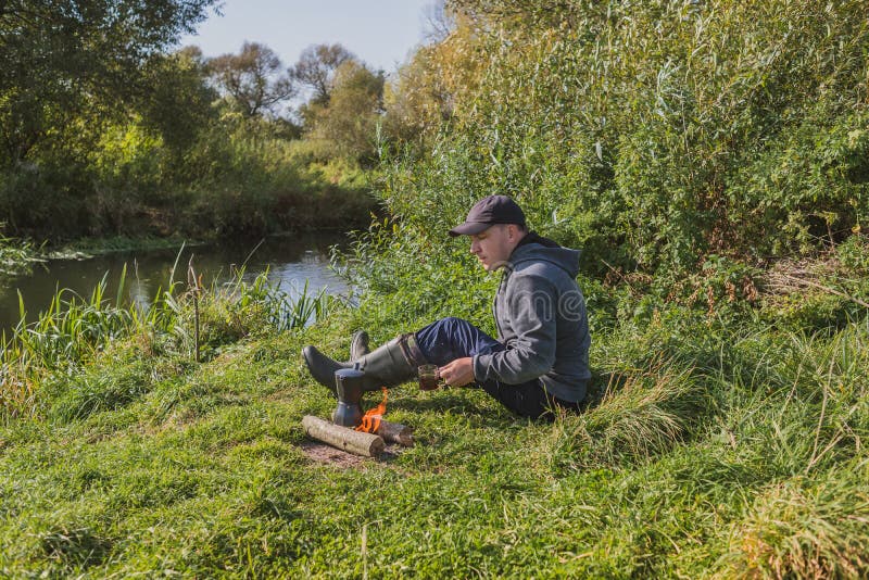 Man Sitting Near a Fire on the River Bank. Rest at Nature. Man Sits ...