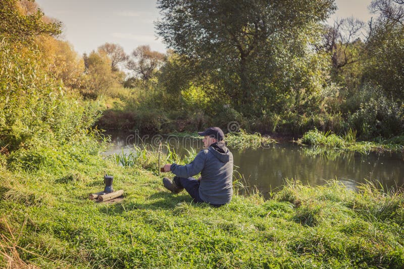 Man Sitting Near a Fire on the River Bank. Rest at Nature. Man Sits ...