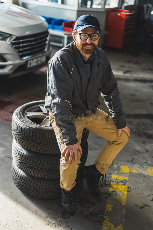 A Man Sitting on a Stack of Car Wheels in a Car Repair Shop Stock Image ...