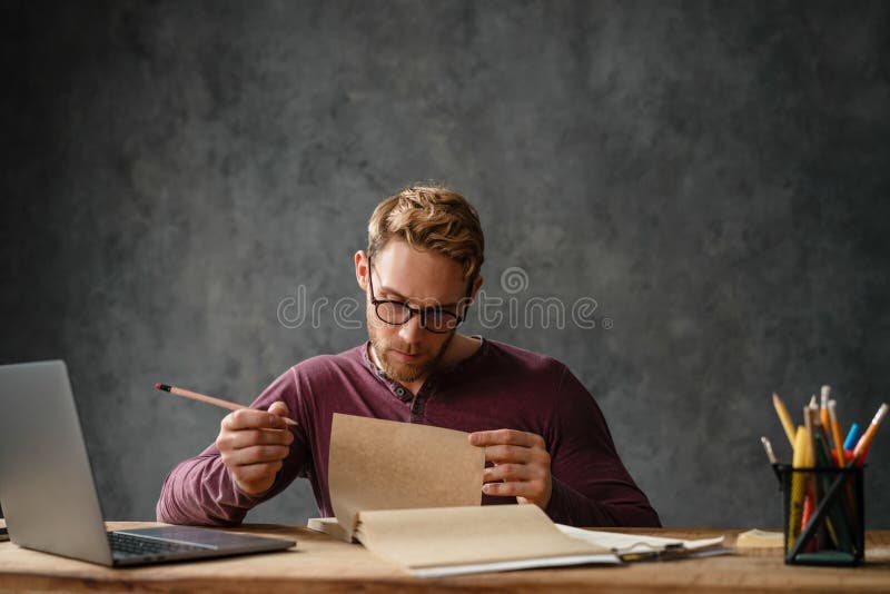 The Man Sitting at the Table while Flipping through Papers in the ...