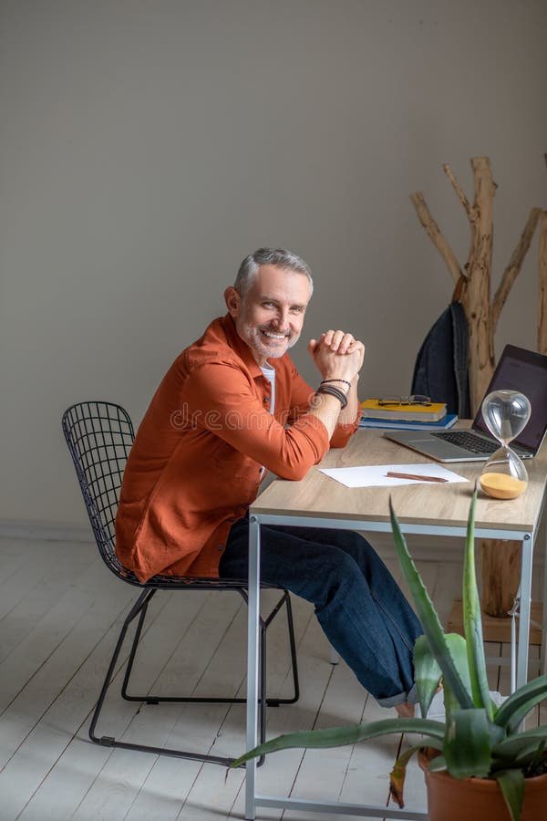 A Man Sitting at the Table in the Offcie and Looking Contented Stock ...
