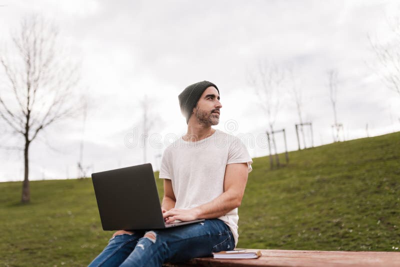 Man Sitting at a Table Using Laptop Outdoors Stock Photo - Image of ...