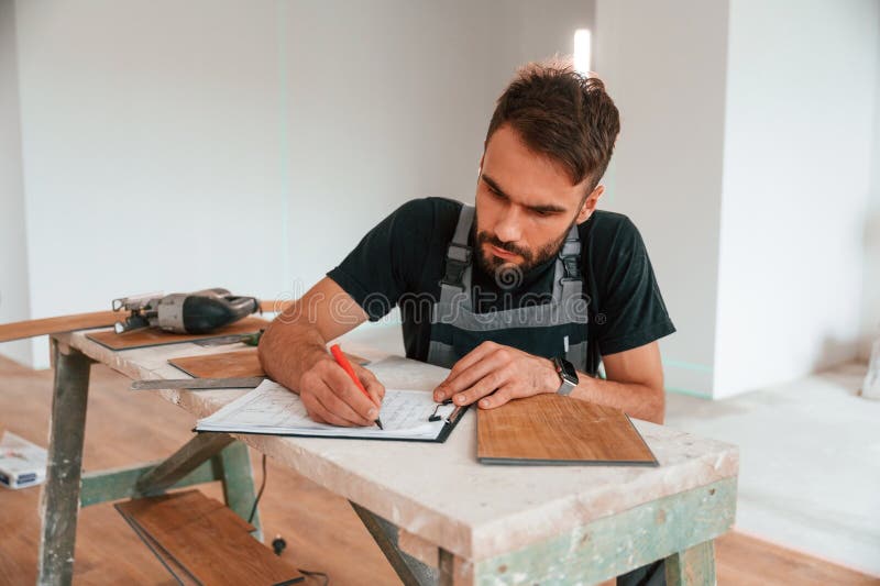 Man Sitting by the Table and Writing Data into Notebook. with New ...