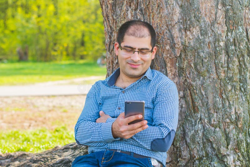 Young Man Sitting Under a Tree Stock Image - Image of male, happy ...