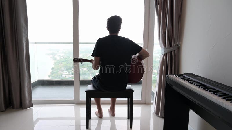 Man Playing Guitar Looking Out Window Stock Video - Video of adult ...