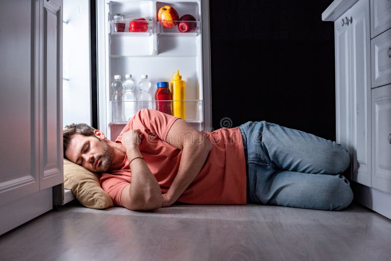 Man Sleeping on Floor in Kitchen Near Open Refrigerator Stock Photo ...