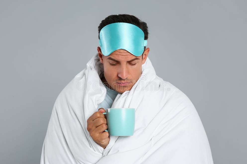 Man in Sleeping Mask Wrapped with Blanket Holding Cup on Grey ...
