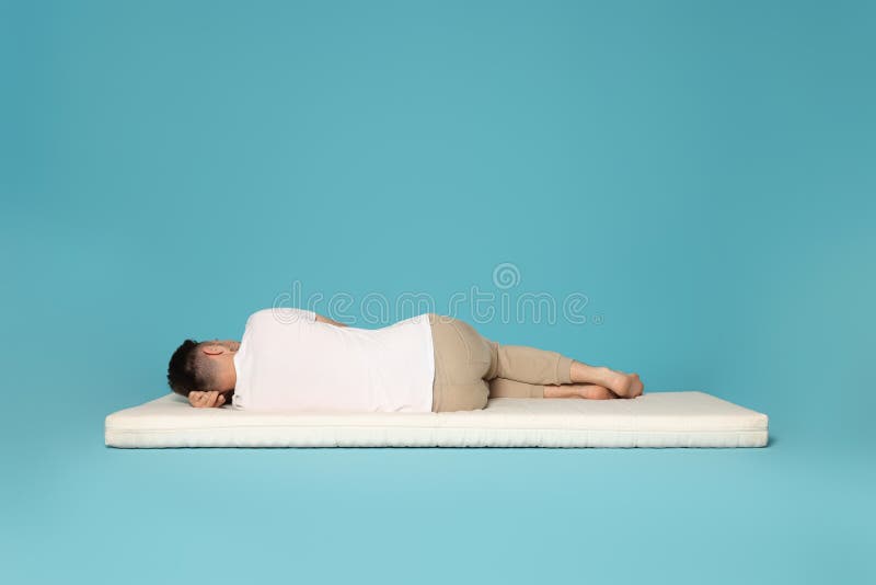 Man Sleeping on Soft Mattress Against Light Blue Background, Back View ...