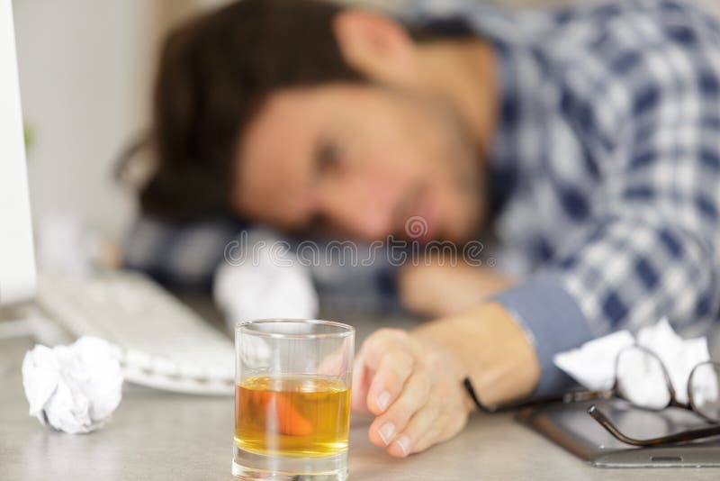 Man Slumped Across Desk Reaching for Alcoholic Drink Stock Photo ...
