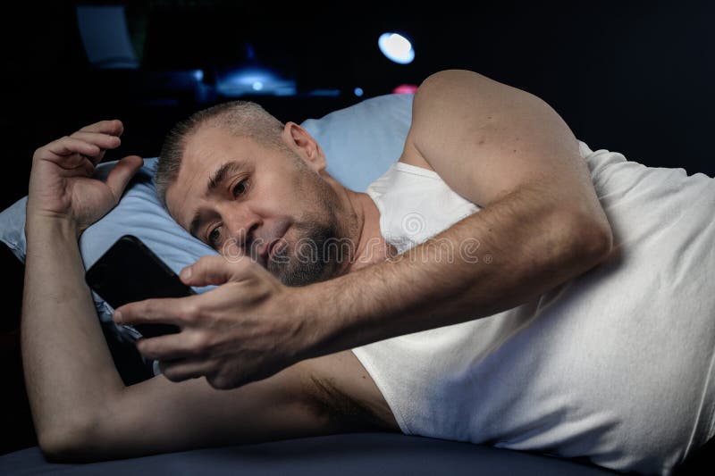 Man with Smartphone in Bed at Night. Handsome Man Using Mobile Phone in ...