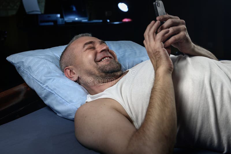 Man with Smartphone in Bed at Night. Handsome Man Using Mobile Phone in ...