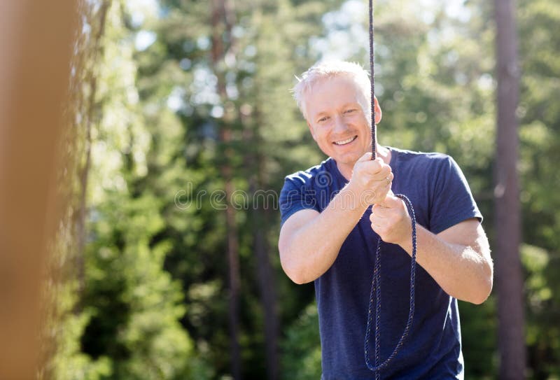 Man Smiling while Holding Rope in Forest Stock Photo - Image of looking ...