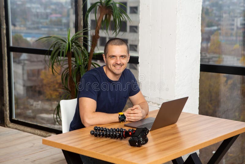 Man Smiling and Looking in Camera. Laptop and Camera on the Table Stock ...