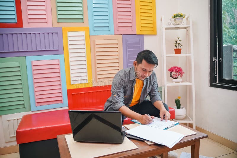 Man Smiling while Writing and Working Using Laptop at Home Stock Image ...
