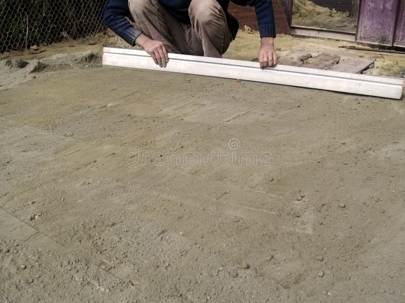 A Man Smooths the Surface of a Dry Sand-cement Mixture on the Ground ...