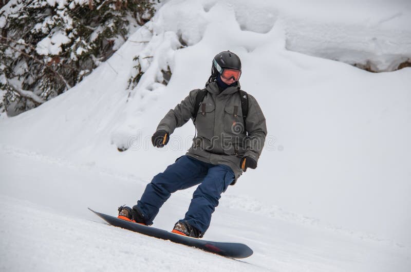 A Man on a Snowboard Rides Down the Side of the Mountain Stock Image ...