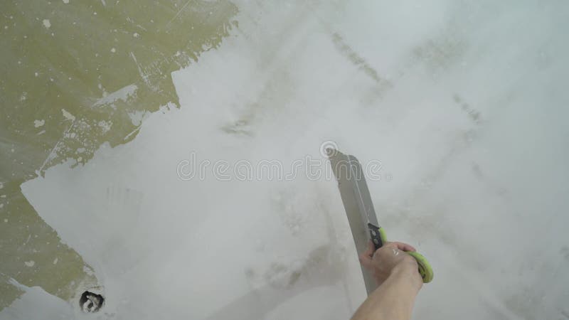 Man with a Spatula and Putty, Applies Mastic To the Ceiling To Level ...