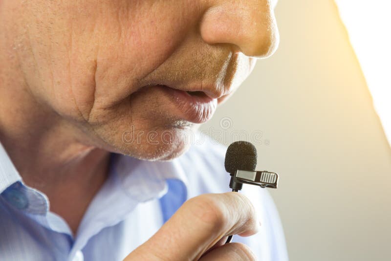 The Man Speaks into a Small Microphone in a Low Voice. Stock Image ...