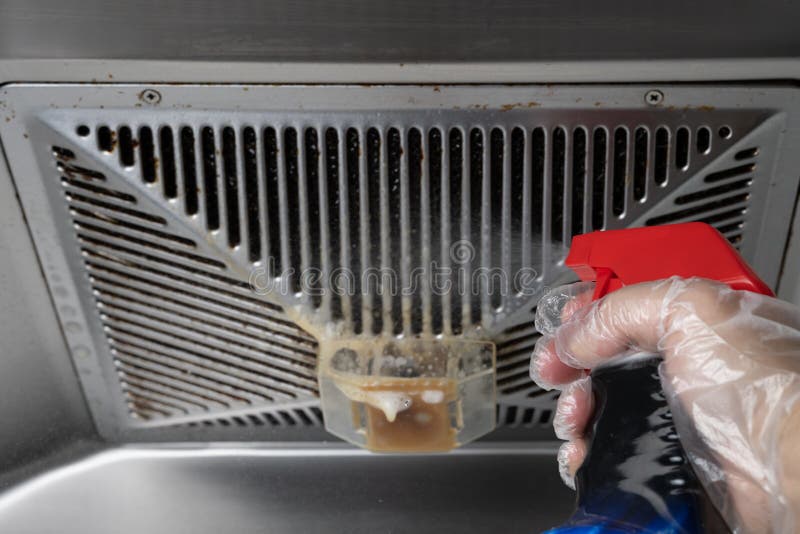 A Man Spraying Chemical Liquid To an Oily Filter Hood of a Kitchen ...