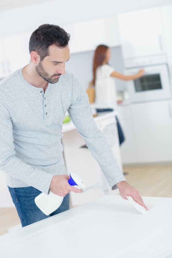 Man spraying kitchen table stock photo. Image of bottle - 120758814