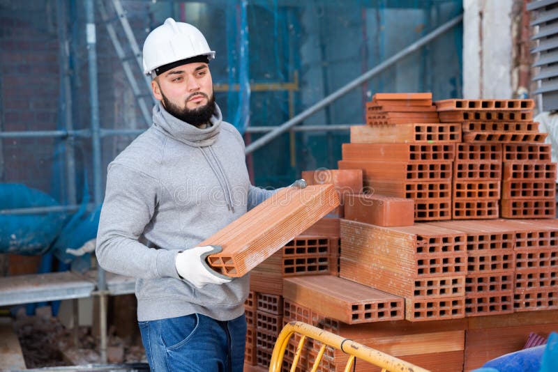 Man stacking red bricks stock photo. Image of positive - 204786548