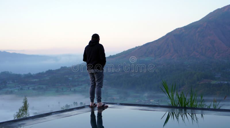 Man Standing Alone from Behind on the Edge of the Pool at Sunrise with ...