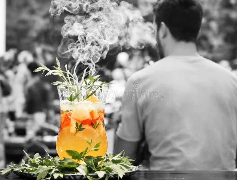 A Man is Standing Behind a Table with a Glass of Liquid in Front of Him ...