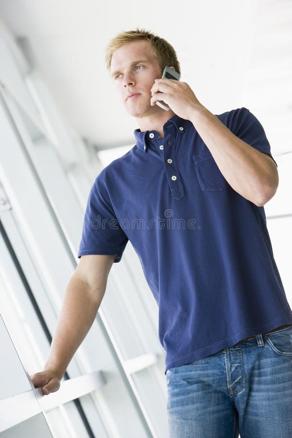 Man Standing in Corridor Smiling Using Phone Stock Image - Image of ...