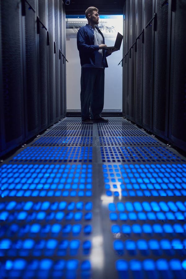 Man Standing in Data Server Room Holding Laptop Computer Stock Photo ...