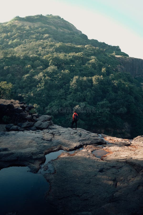 Man Standing on the Edge of a Cliff Looking Up at the Mountain Covered ...