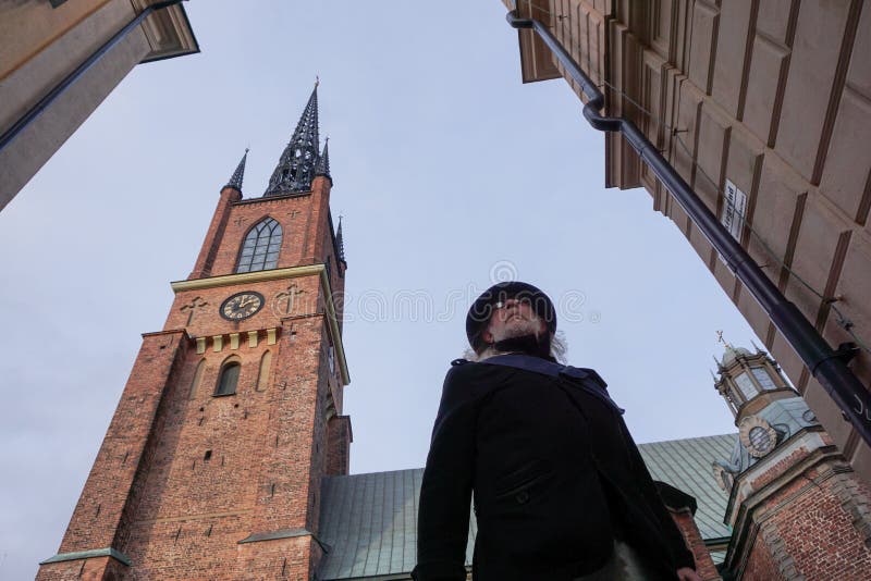 A Man Standing in Front of a Brick Building with a Clock Tower Stock ...