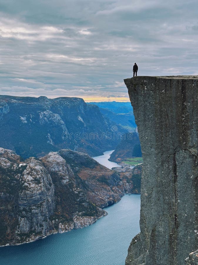 A Man on the Top of a High Cliff Overlooking a Lake Stock Image - Image ...