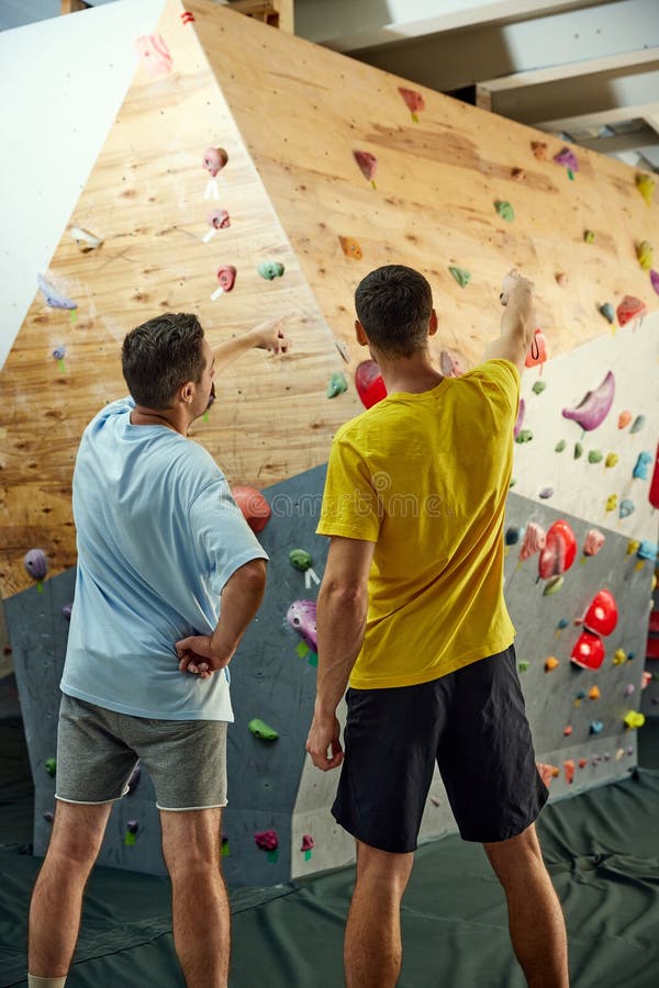 Man Standing with Instructor, Looking and Pointing on Climbing Wall ...