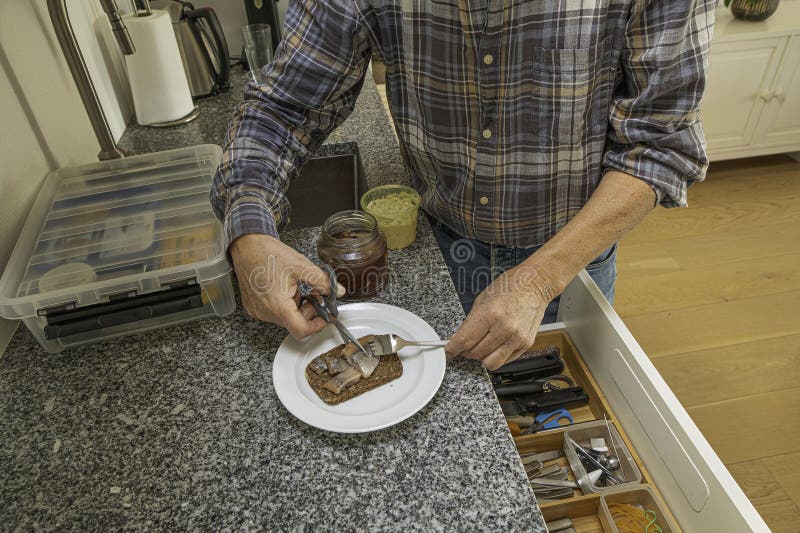 A Man is Standing in the Kitchen Making a Sandwich with Herring on a ...