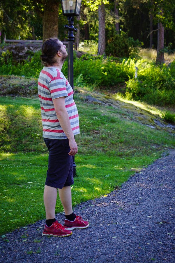A Man Standing Looking Up in a Park Stock Photo - Image of shorts, lawn ...