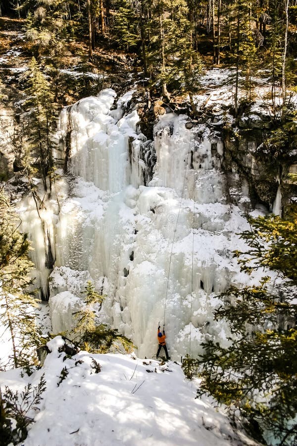 A Man is Standing on a Snow-covered Cliff, Looking Down at the Ice ...