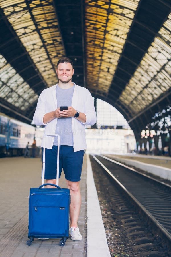 Man Standing with Suitcase at Railway Station Waiting for Train Using ...