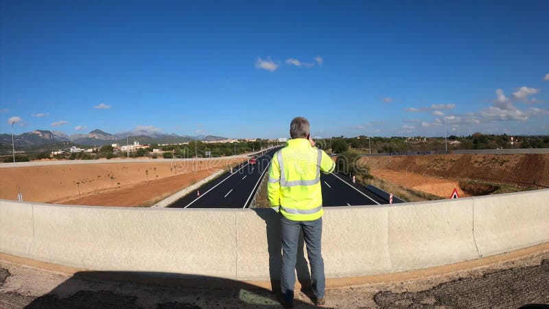 A Man Standing Talking on the Phone in a Yellow Safety Jacket from a ...