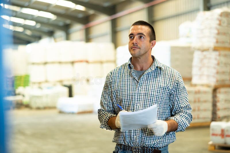 Man Standing in Warehouse and Verifying Documents with Presence of ...