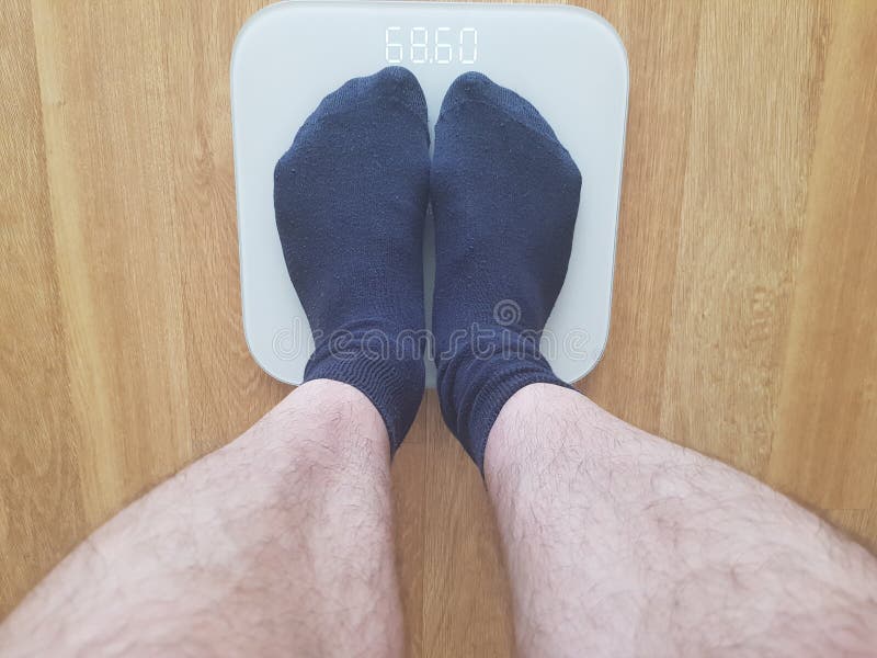 Man Standing on a Weight Scale and Holding His Feet in Socks. Stock ...